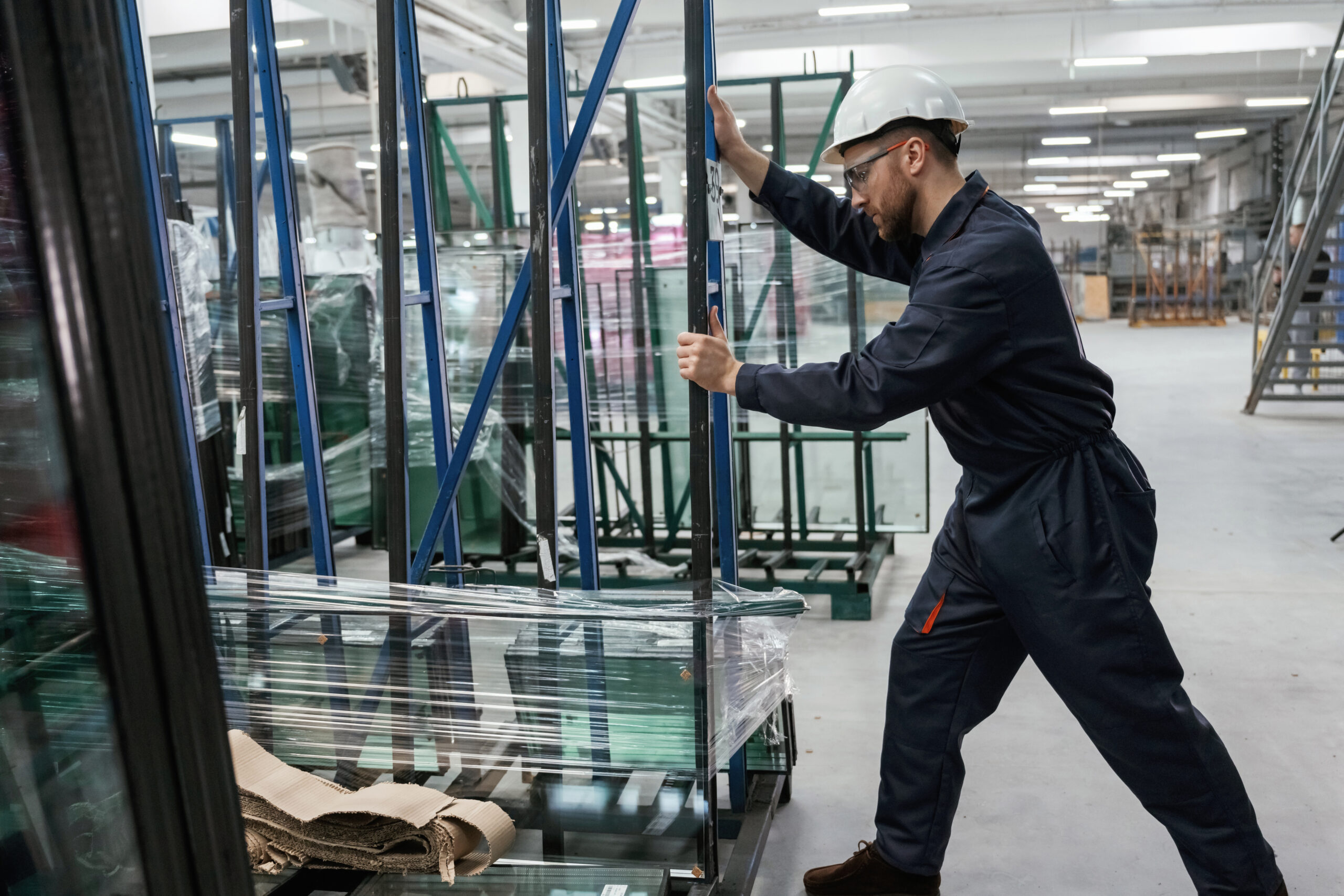 Moving the parts of windows. Factory worker is indoors with hard hat ...